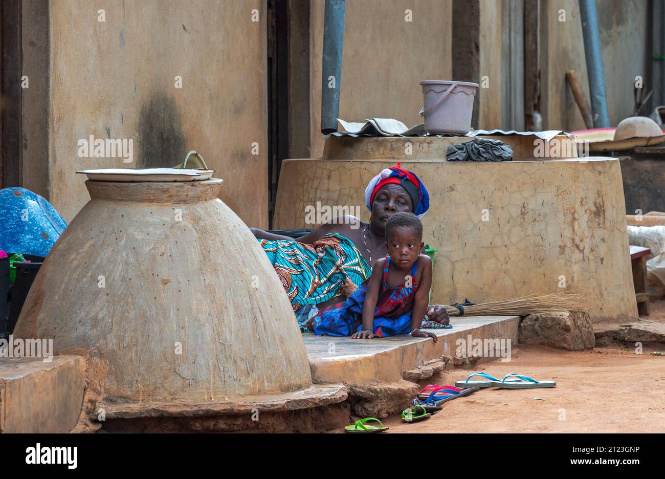 Lome, Togo -- May 14, 2023. A mother and child watch a village Voodoo ...