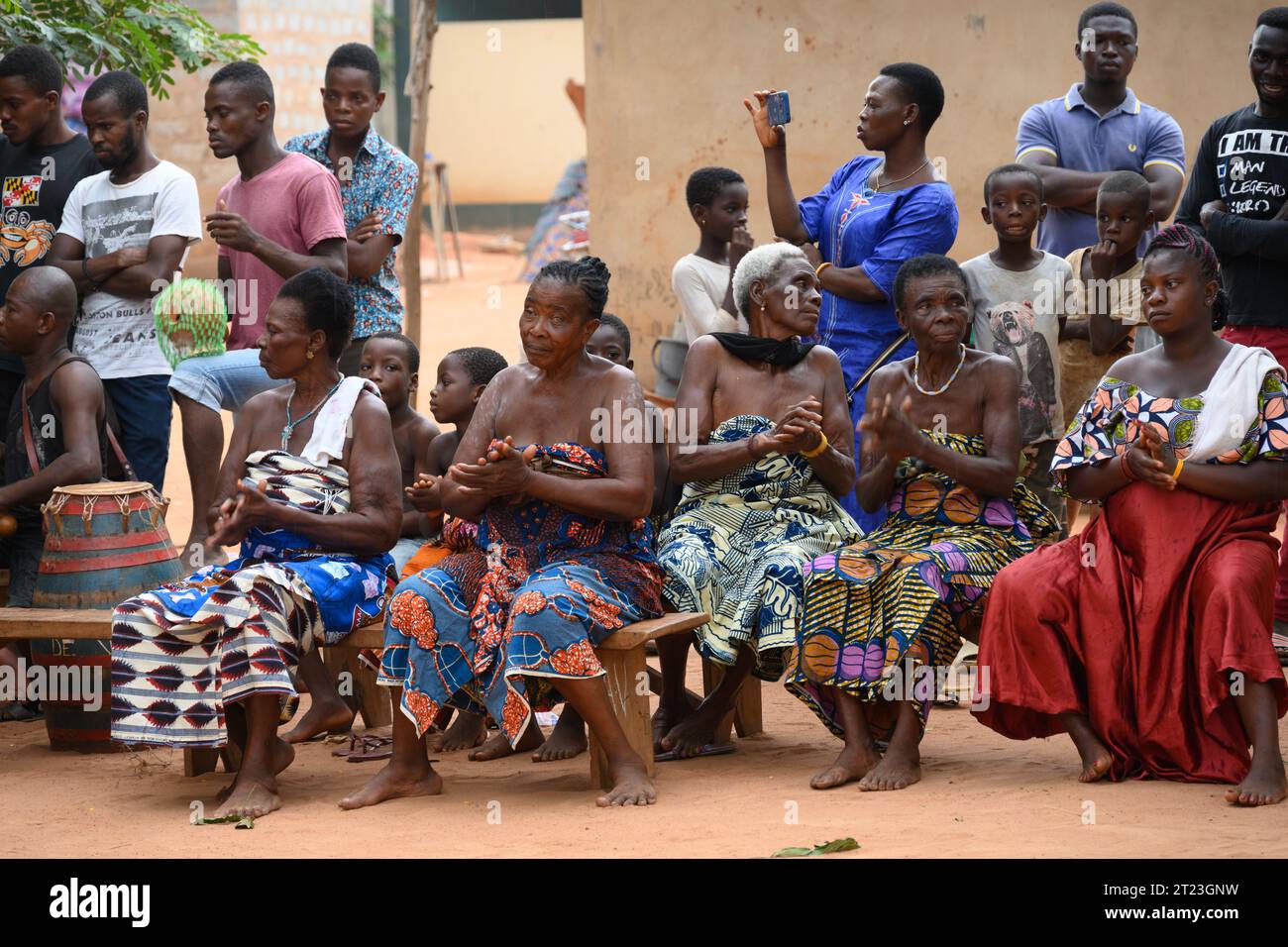 Lome, Togo -- May 14, 2023. Native villagers sit on benches and watch a ...