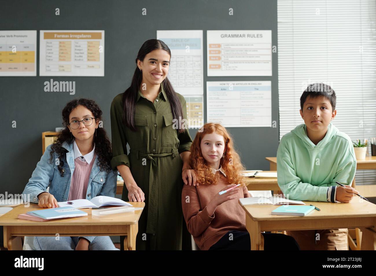 Young successful teacher and group of diligent secondary school learners looking at camera ...