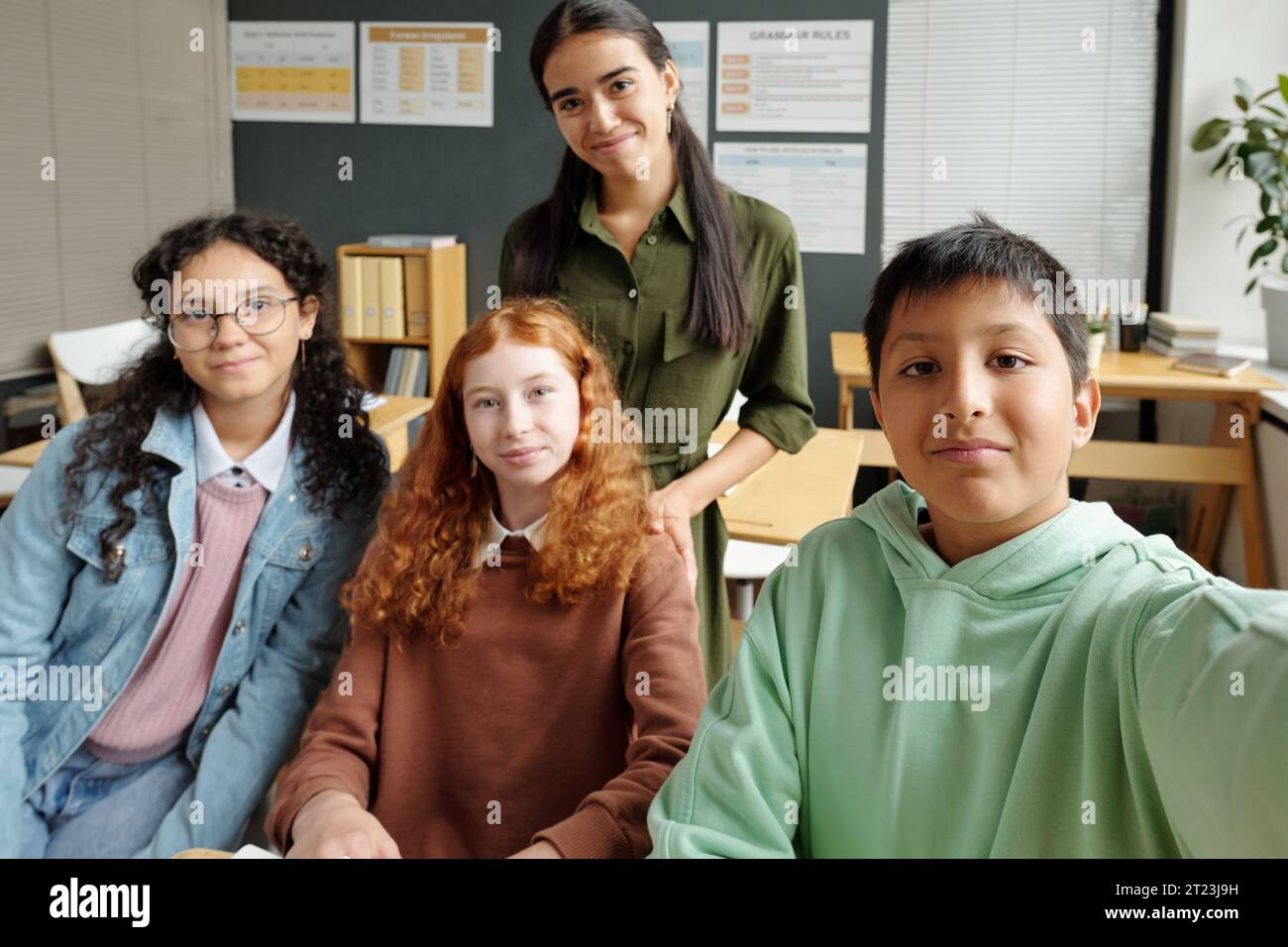 Cute schoolboy taking selfie with two pretty classmates and their ...
