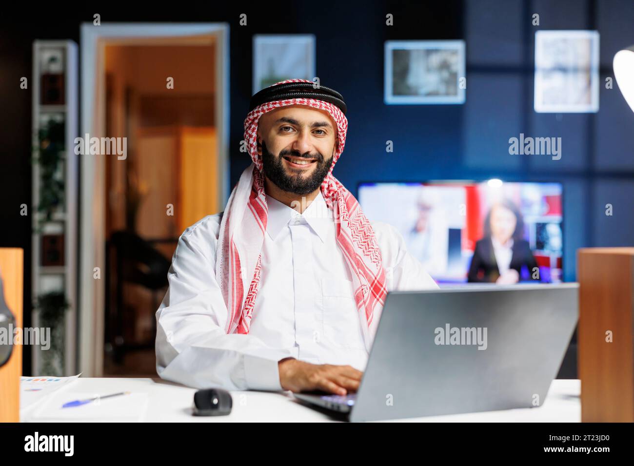 Young man dressed in Arabian clothing using his laptop at the table ...