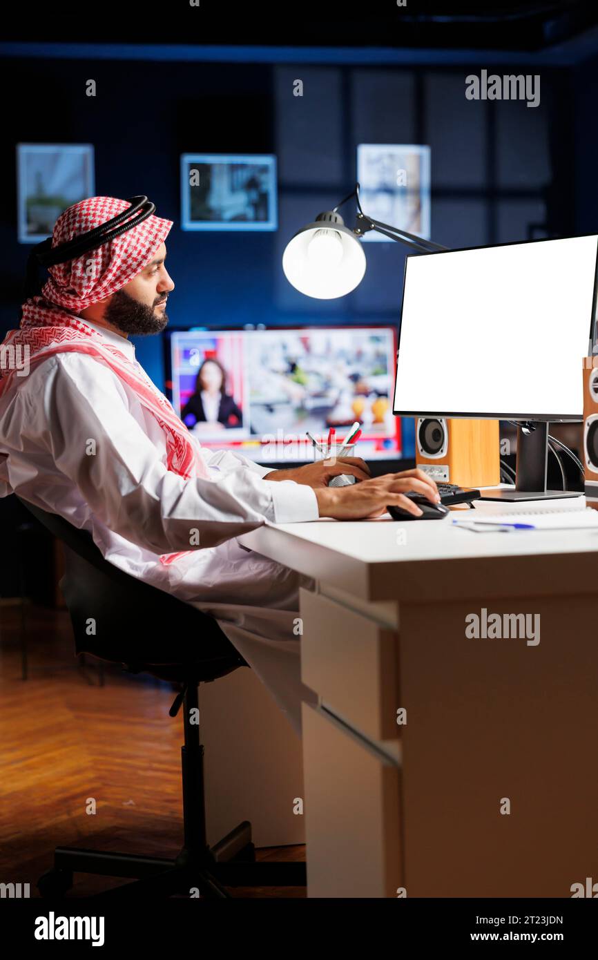 Image shows an Islamic man sitting at his home office desk with the ...