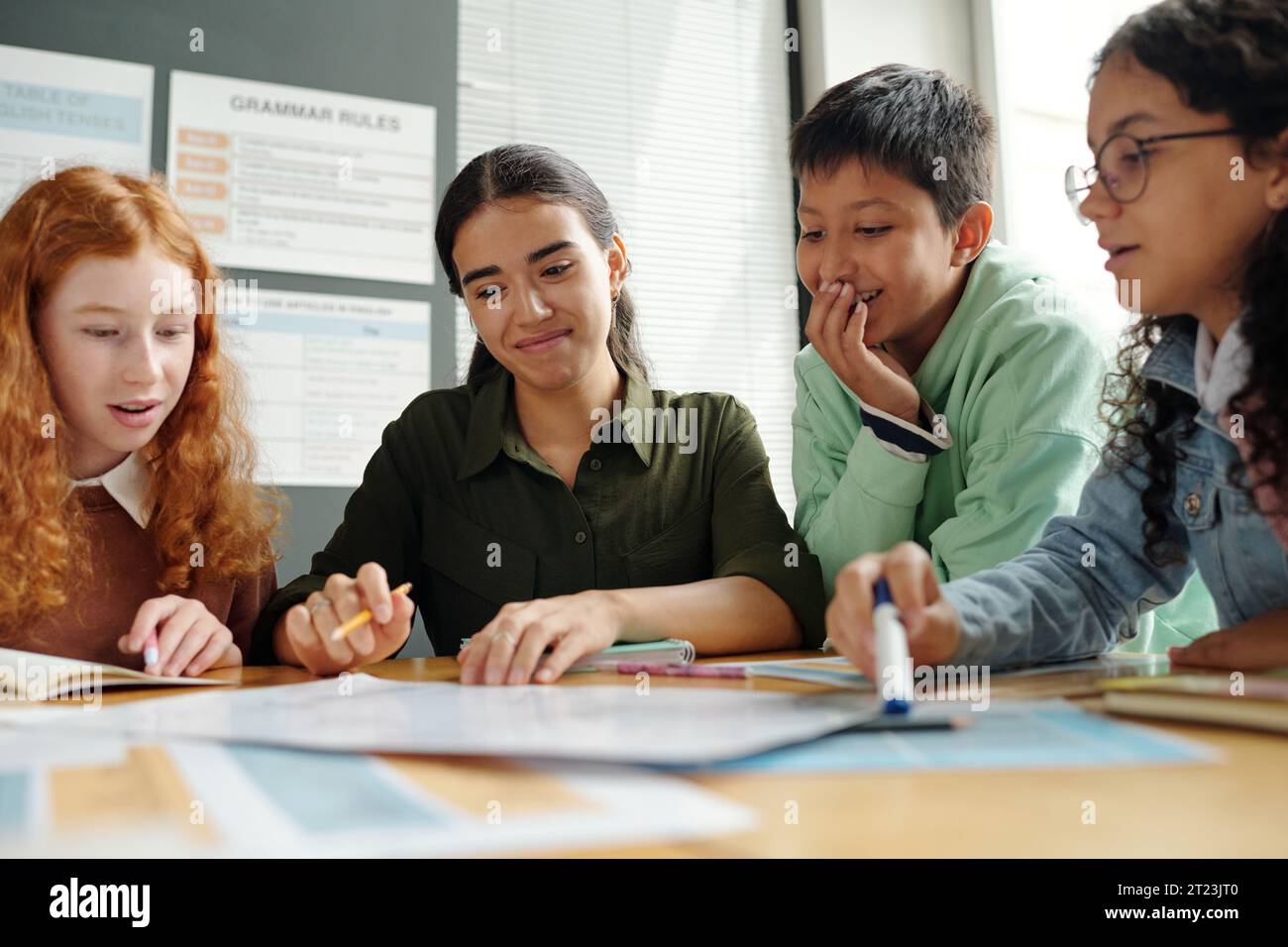 Group of clever schoolkids and their teacher discussing new grammar ...