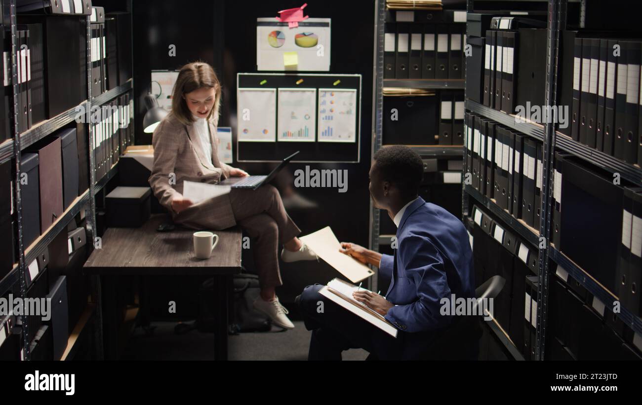 In room crammed with clues and records, caucasian female investigator ...