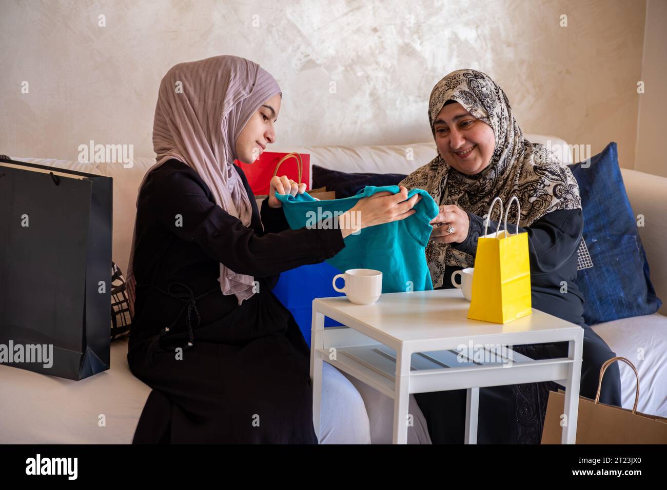 Arabic woman gifting her mother and showing the new clothes after ...