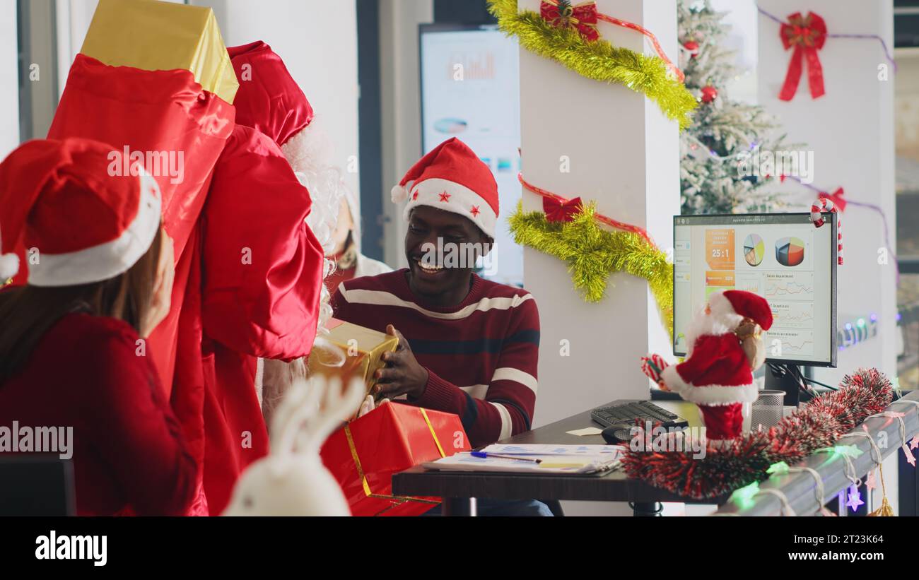 Overjoyed african american worker receiving gifts from Santa Claus in ...
