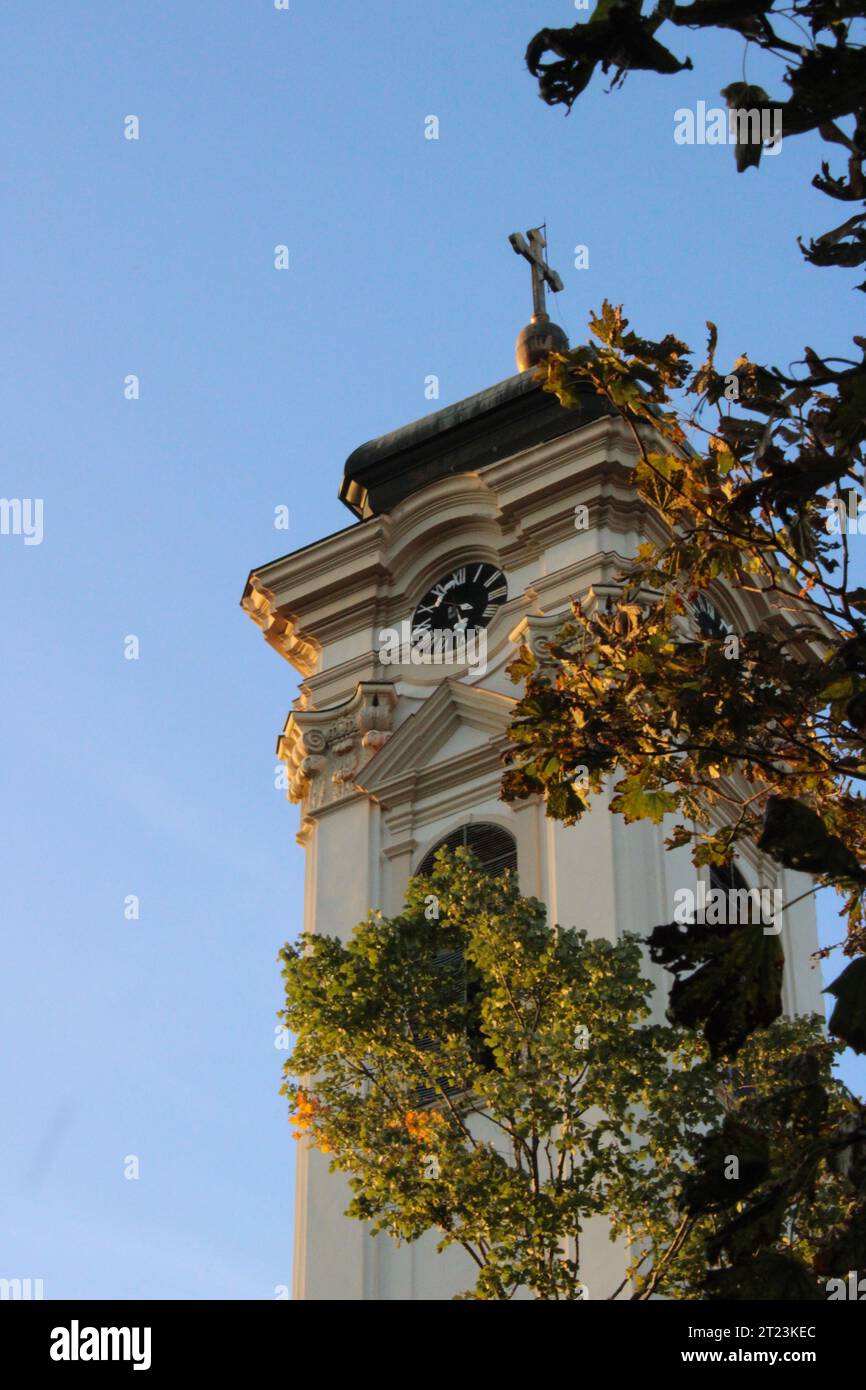 A tall white tower with a clock on its peak situated against a clear ...
