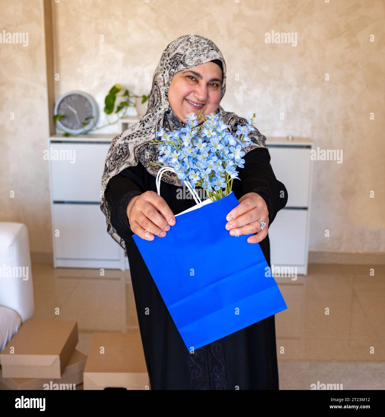 Arabic woman wearing abaya and headscarf holding blue shopping bag ...