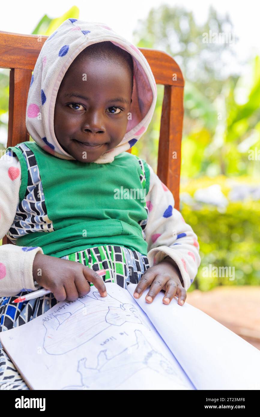 Vertical photo of an African kid drawing on her drawing notebook Stock ...
