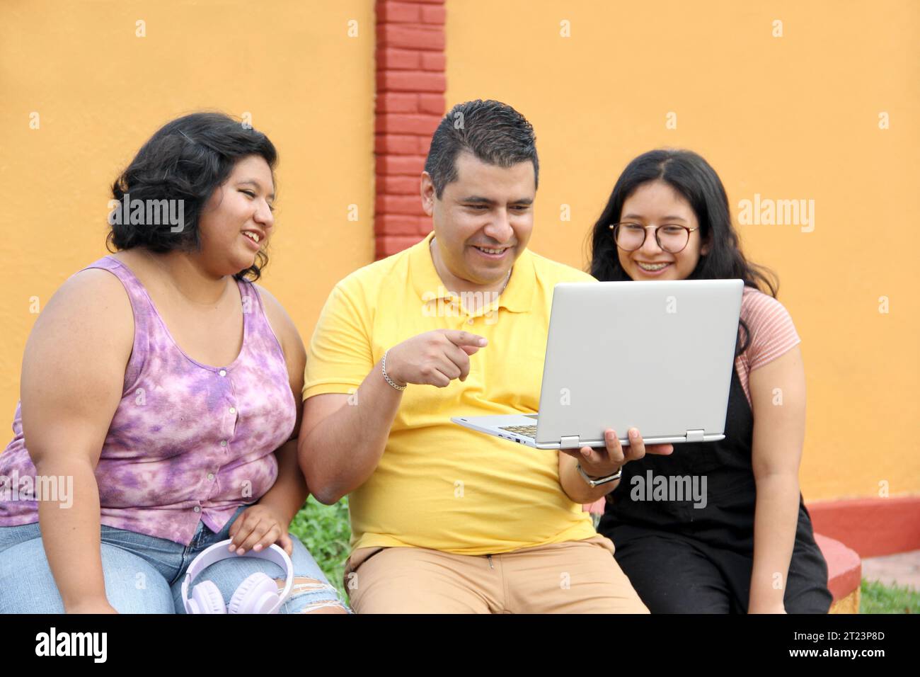 Dark-skinned Latino dad and daughters use laptop together and spend ...