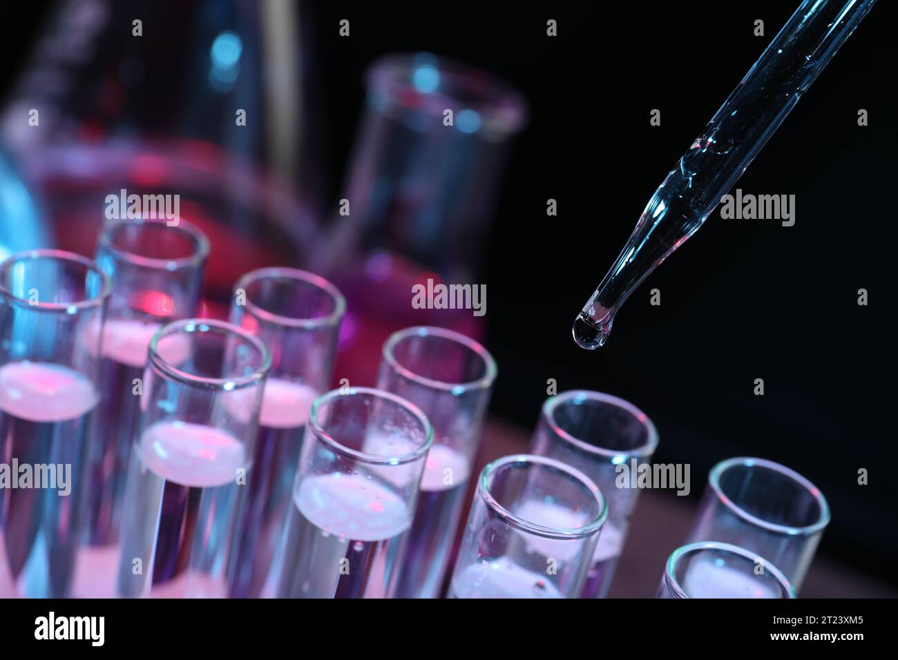 Dripping reagent into test tube on black background, closeup ...