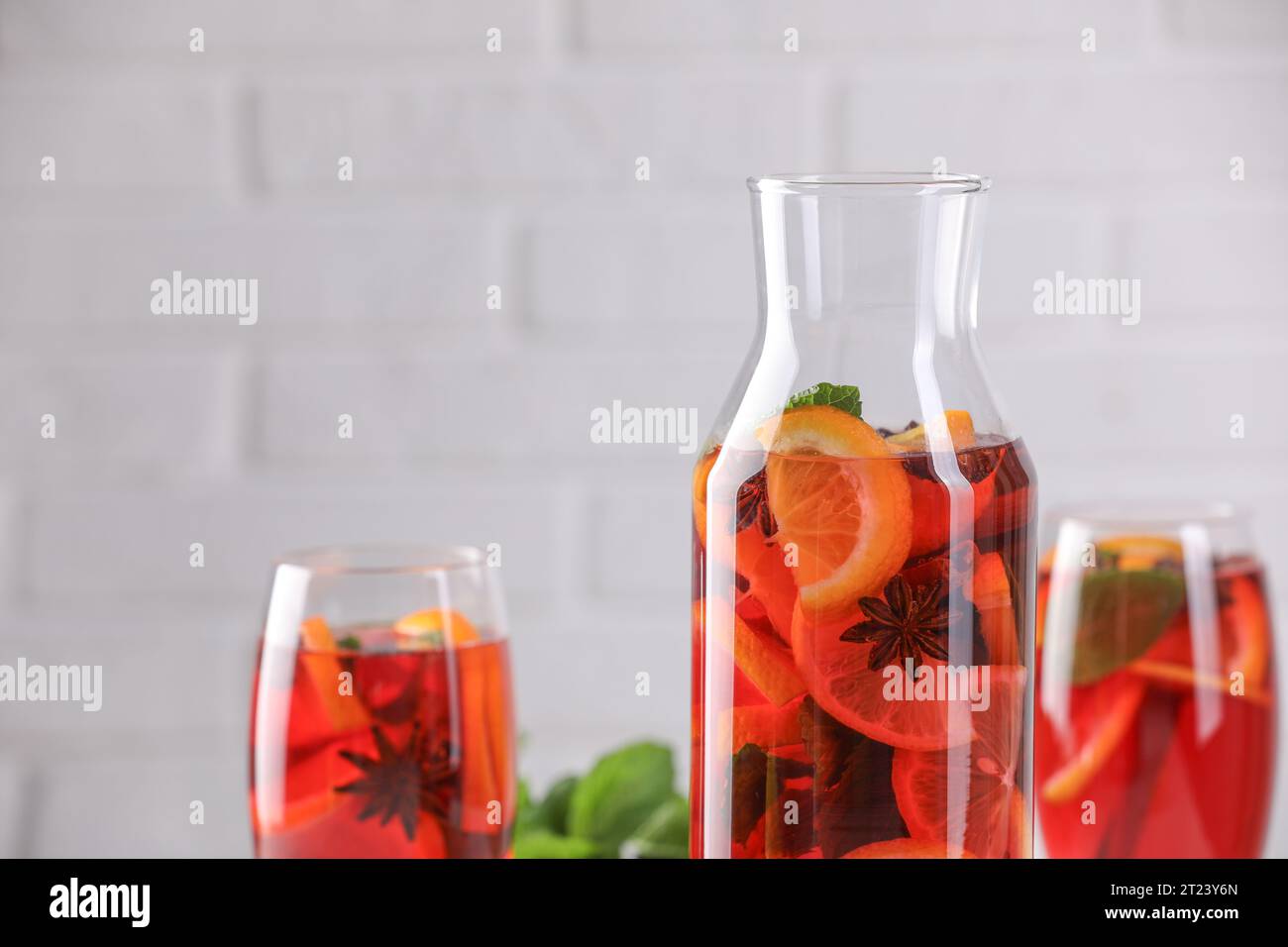 Delicious punch drink against white brick wall, closeup. Space for text ...