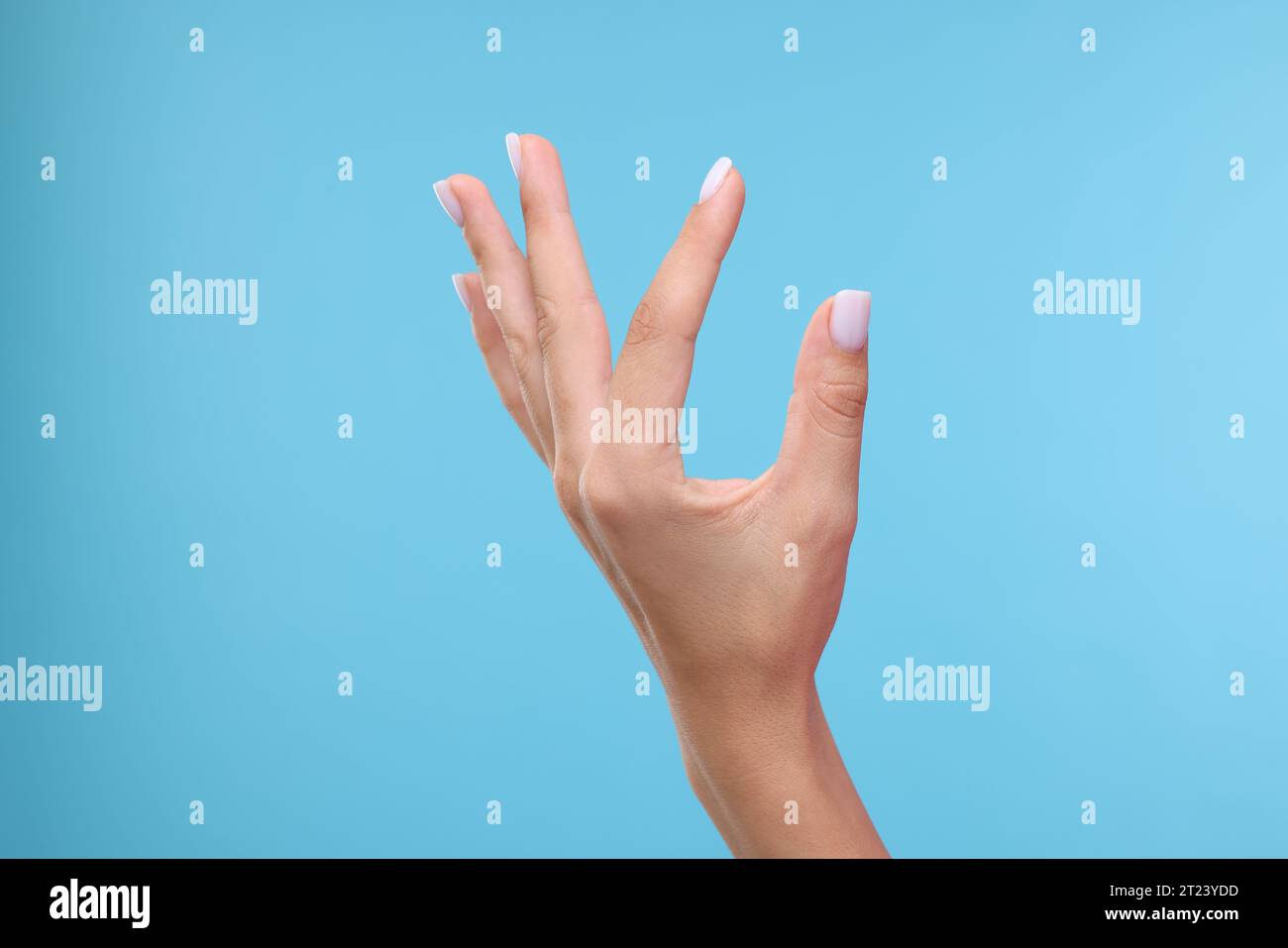 Woman holding something in hand on light blue background, closeup ...