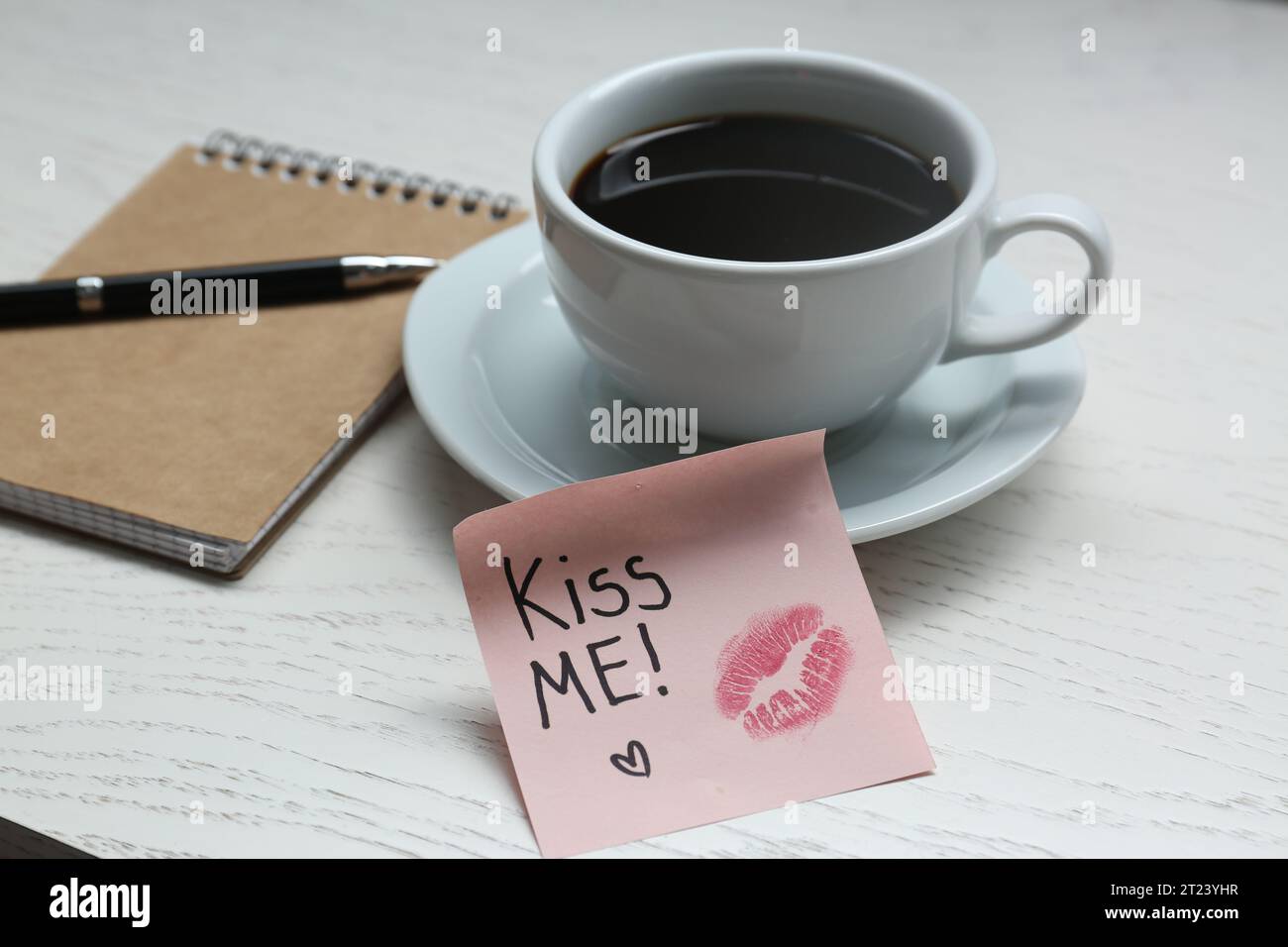 Sticky note with phrase Kiss Me, lipstick mark, cup of drink and ...