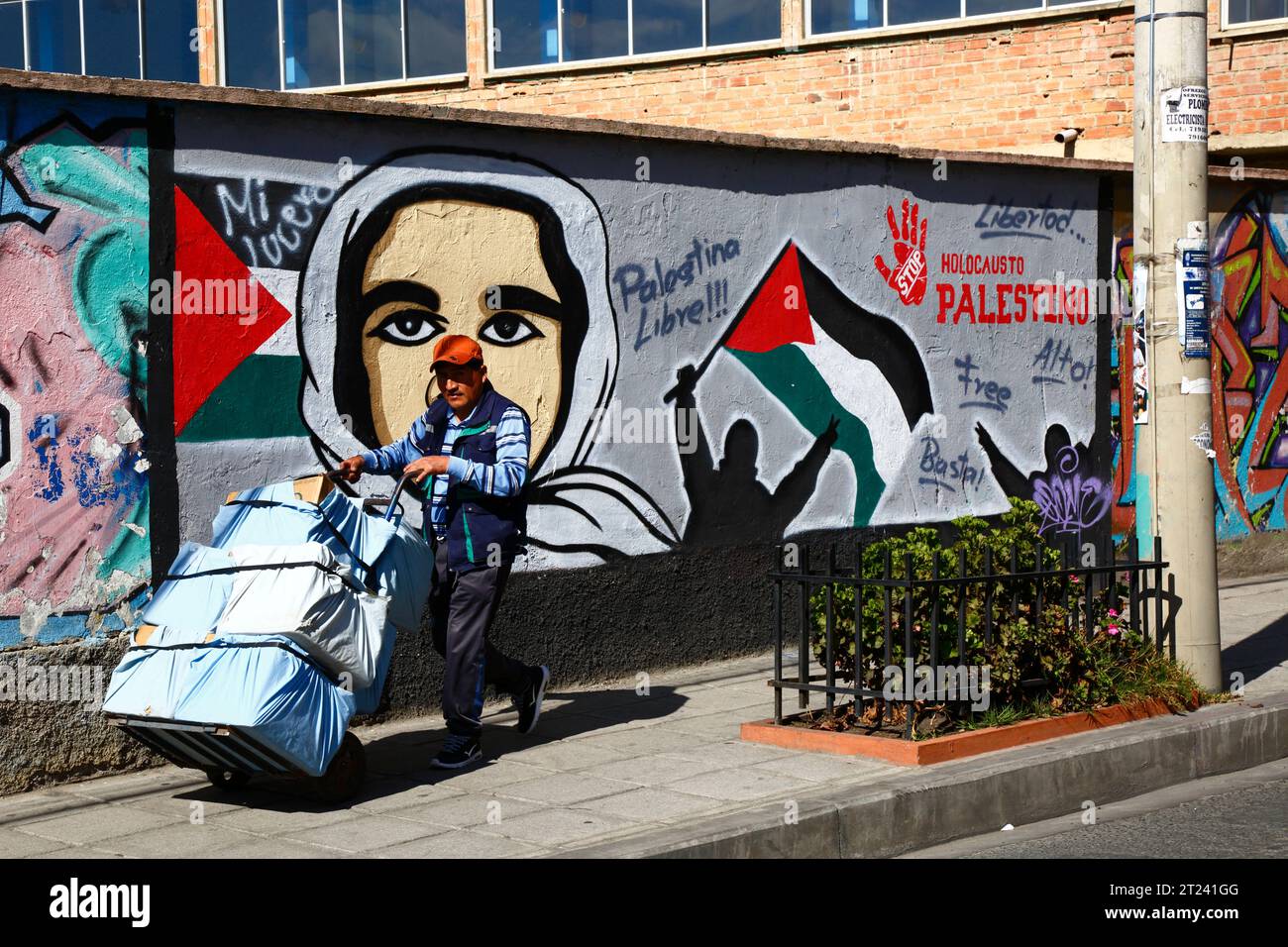 A man pushes a cart past a mural showing support for a free Palestine ...