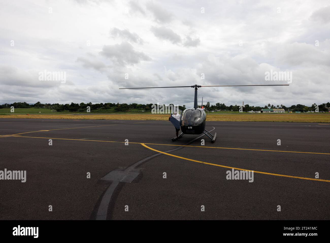 man climbs into a helicopter on an airfield, suva, fiji Stock Photo - Alamy