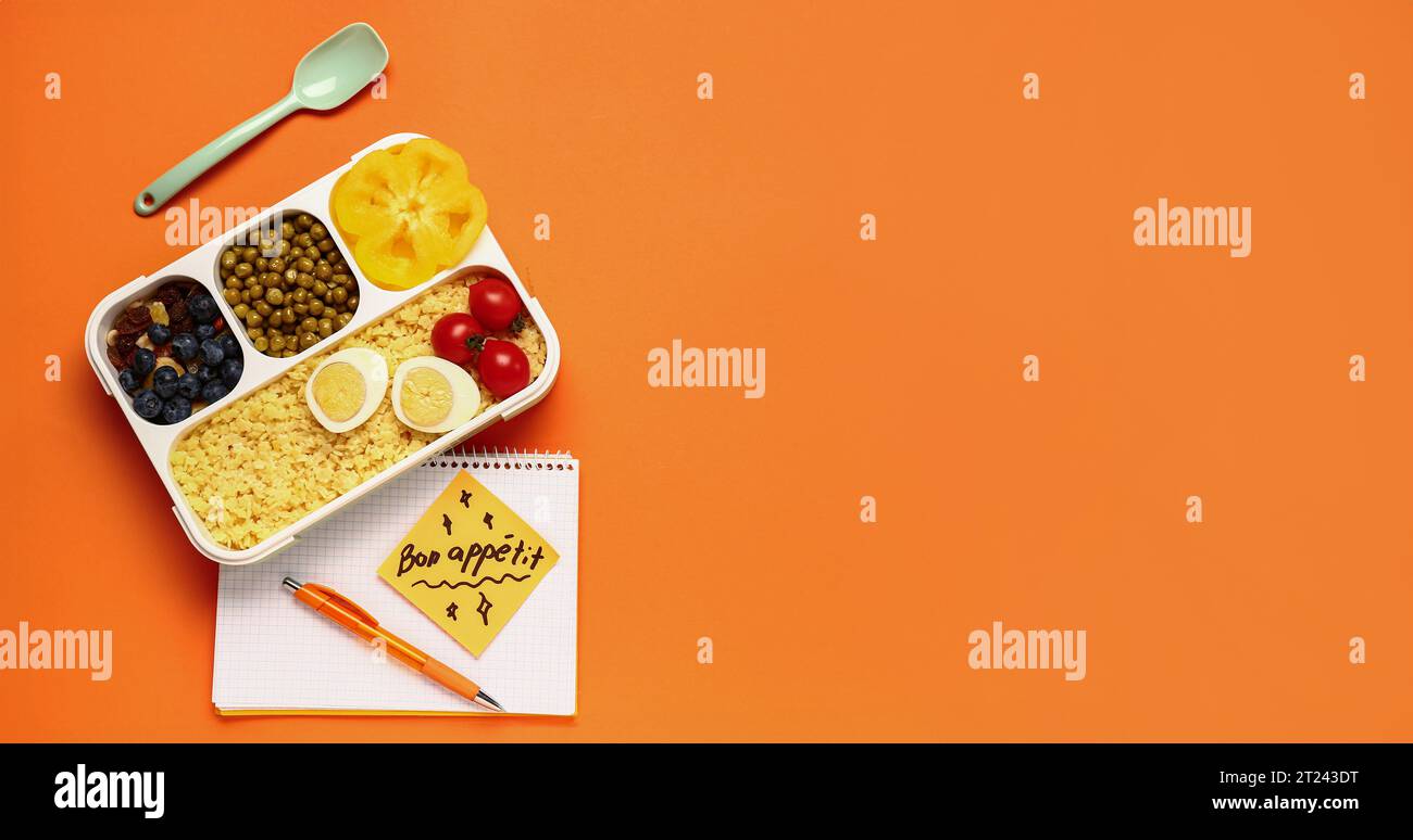 Stationery, tasty food in lunchbox and sticky note with text BON ...