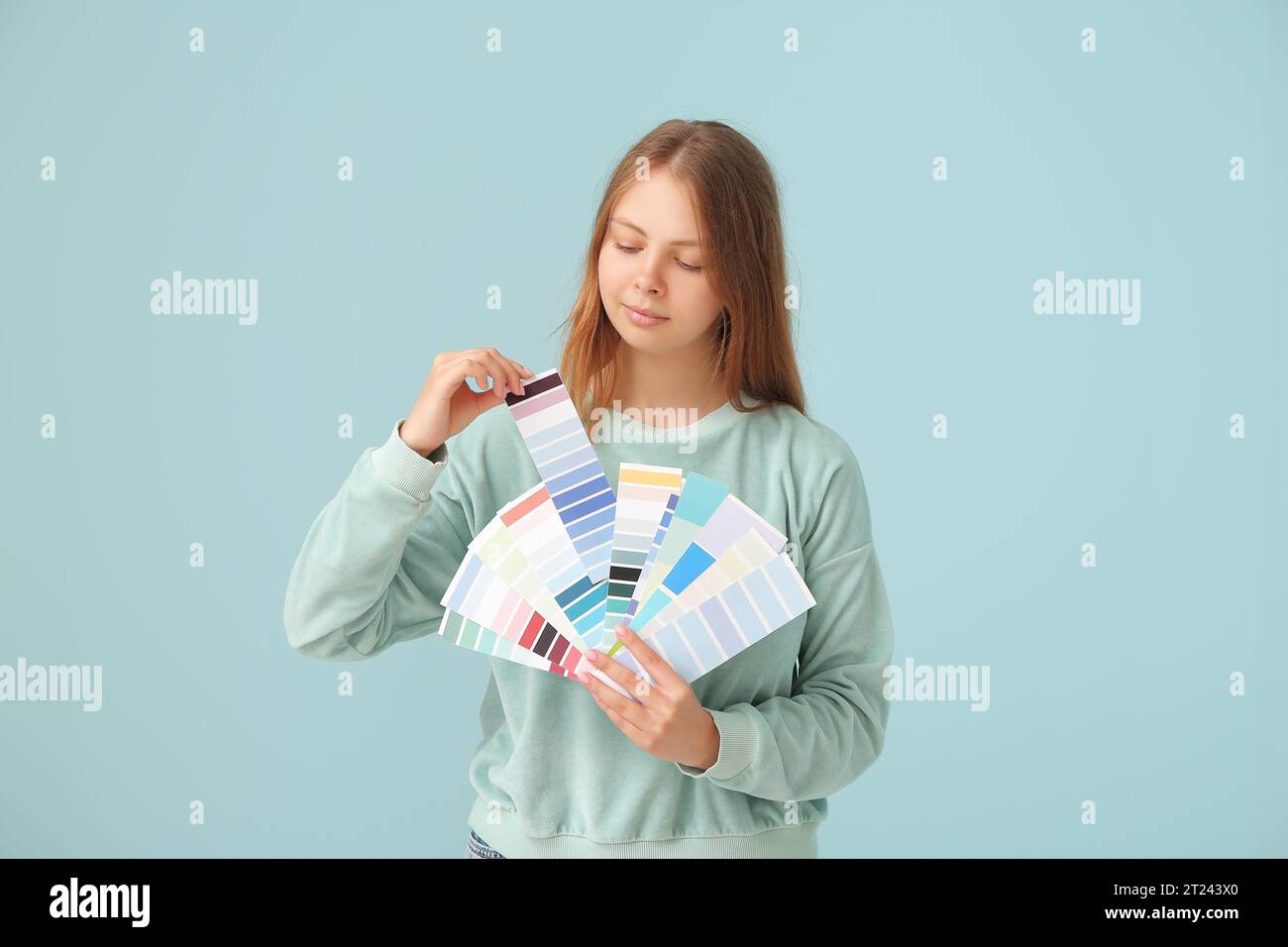Young woman with color samples on light blue background Stock Photo - Alamy