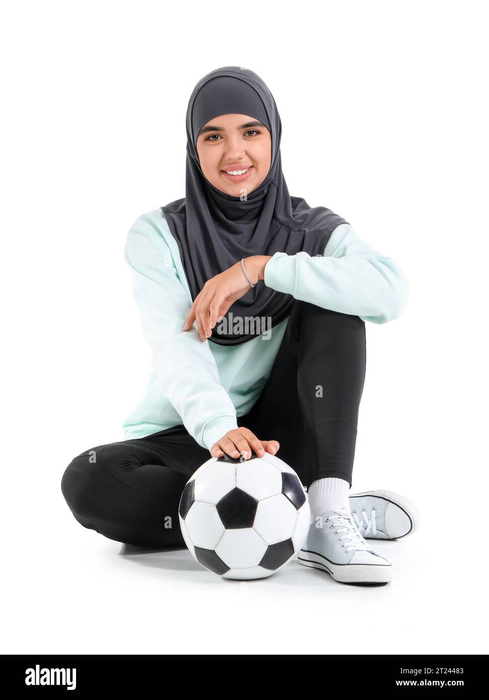 Young Muslim woman with soccer ball sitting on white background Stock ...