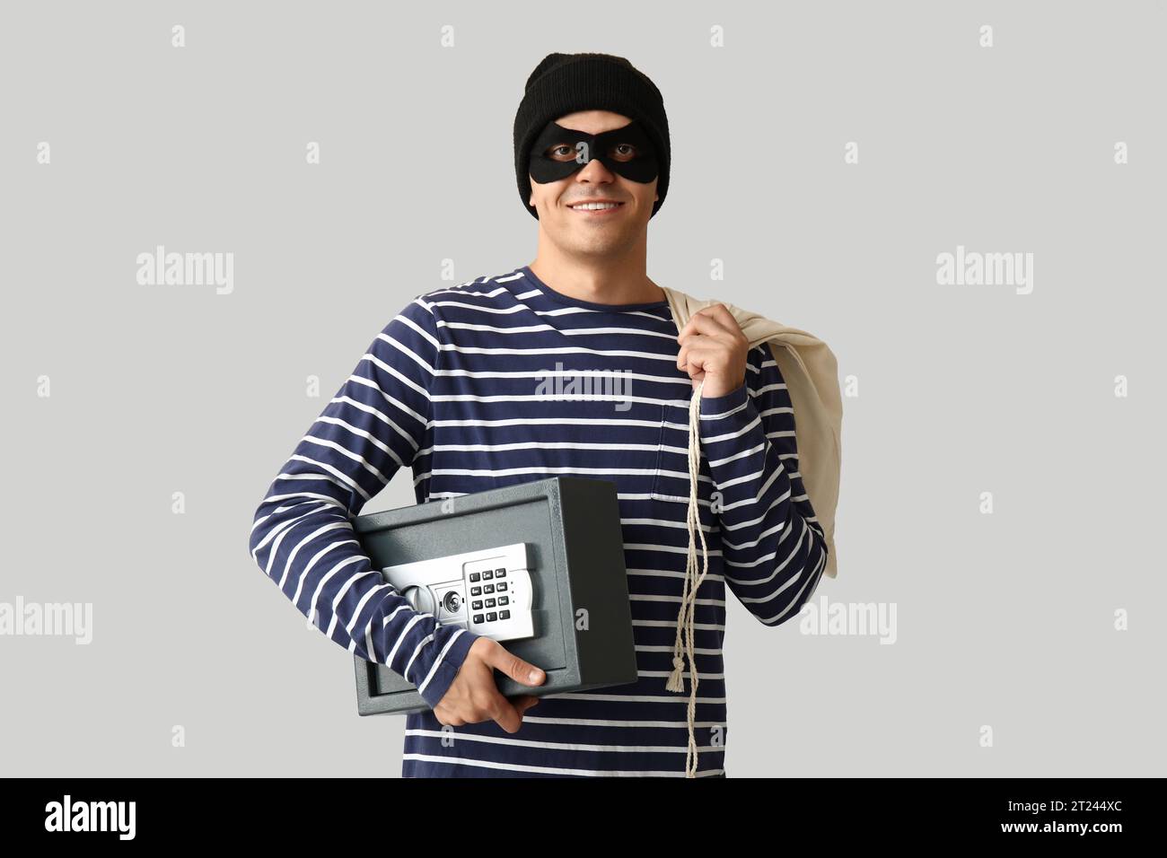 Male thief with bag and safe box on grey background Stock Photo - Alamy