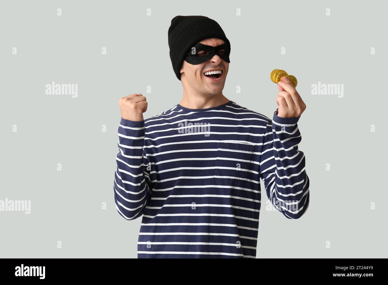 Happy male thief with golden coins on grey background Stock Photo - Alamy