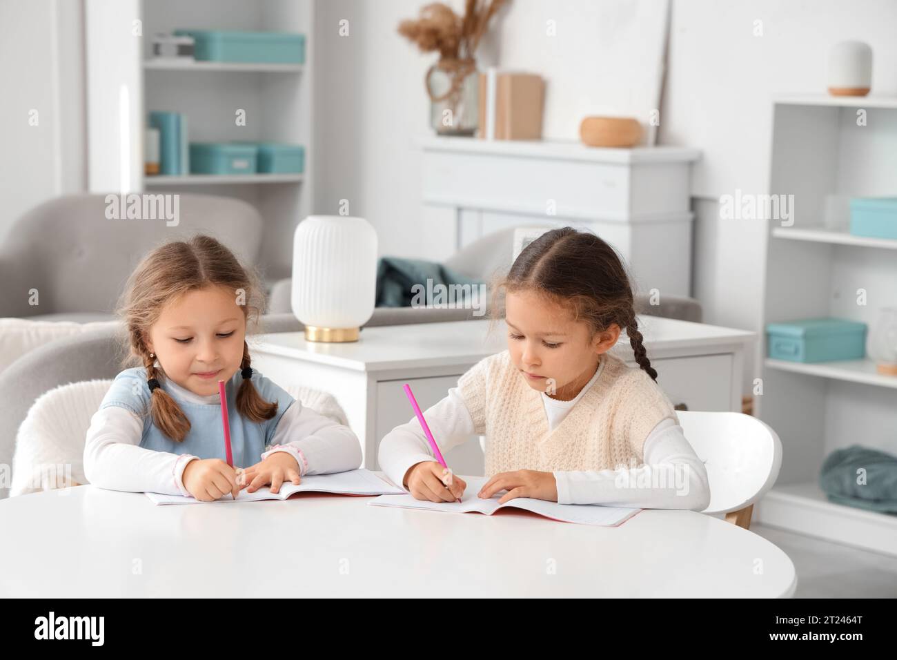 Cute little girls writing in copybooks at home Stock Photo - Alamy