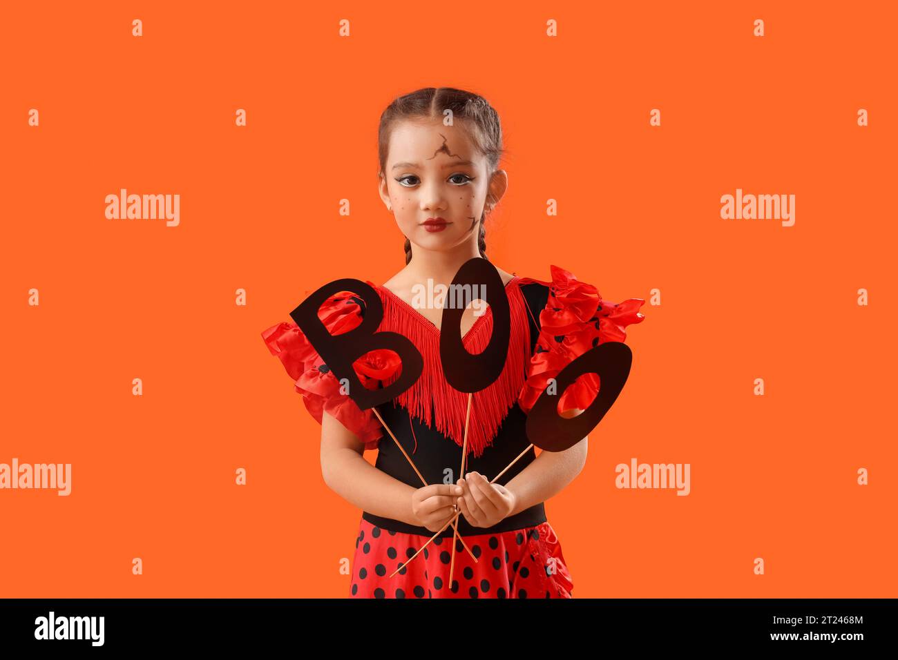 Little Asian girl dressed for Halloween with word BOO on orange ...