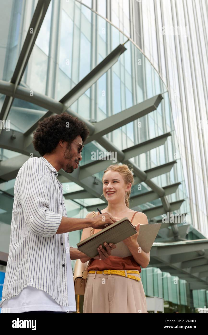 Excited young businesswoman looking at coworker singing document when ...