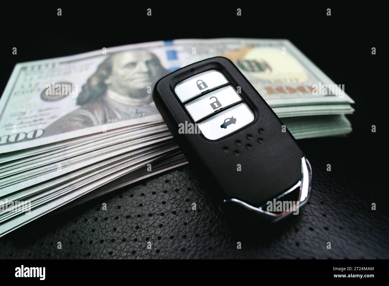 Car key or keyless remote and usd dollar banknotes on a black leather ...