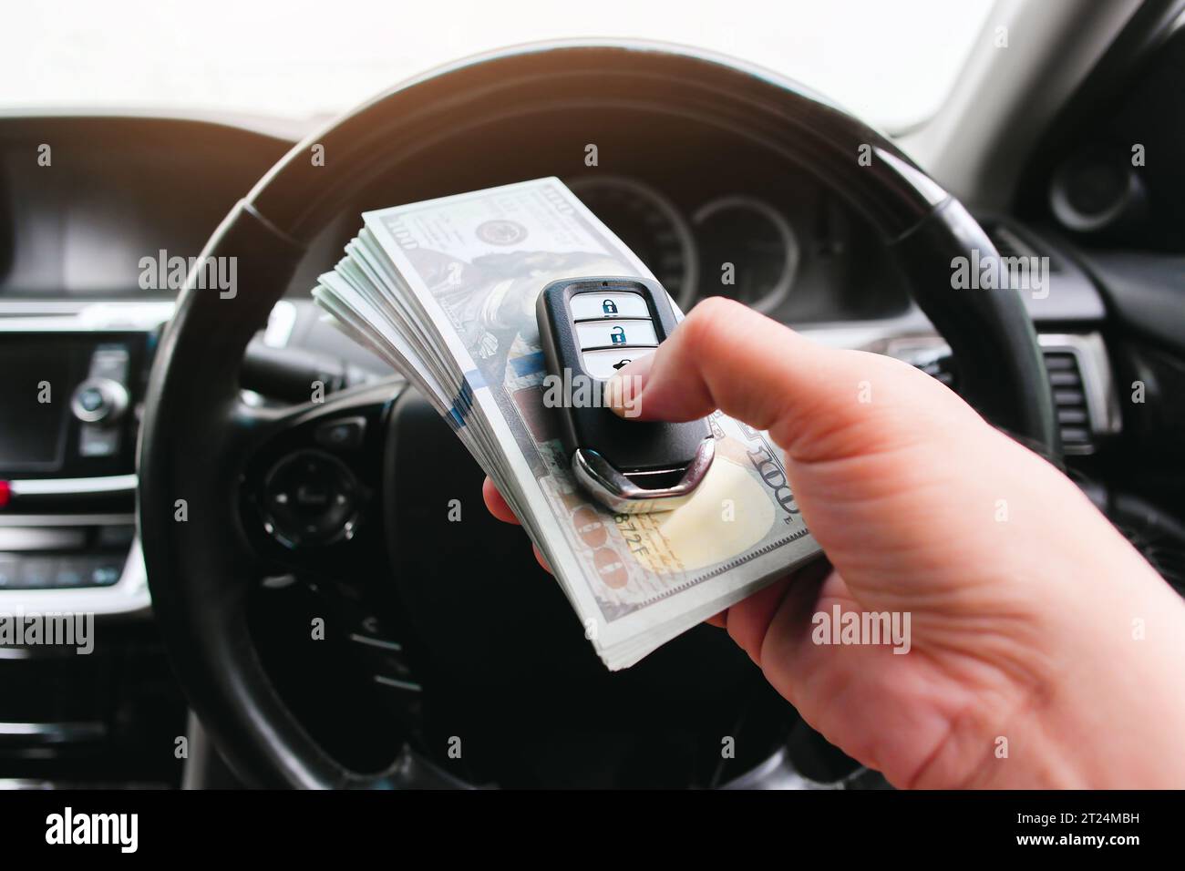Driver hand holding a car key or keyless remote and usd dollar ...
