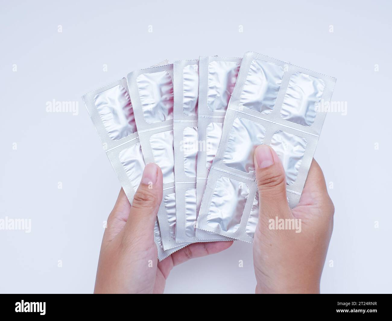 hand holding pile of tablets pills in silver blister packaging isolated ...