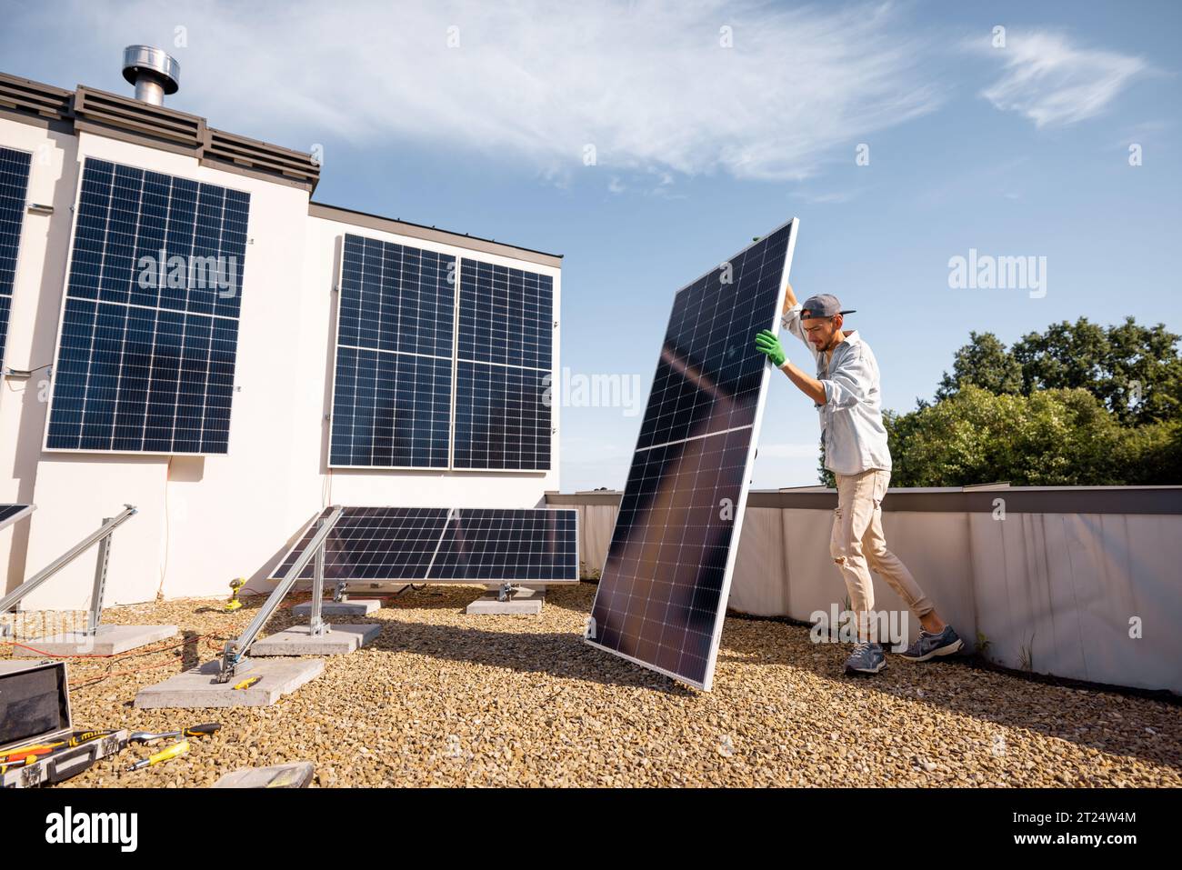 Man installing solar panels on a rooftop Stock Photo - Alamy