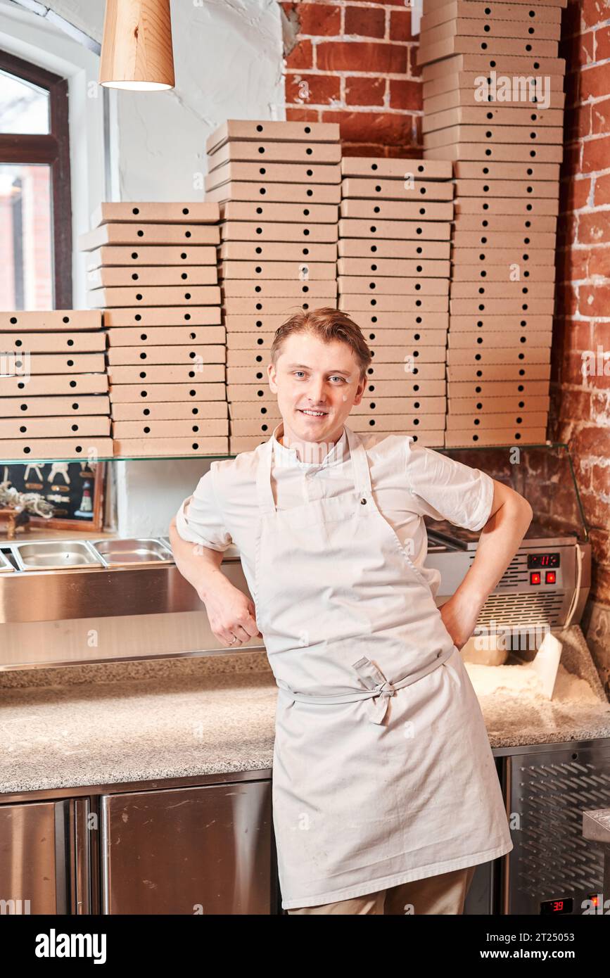 The chef prepares pizza in a neapolitan pizzeria. Cook in a apron in ...
