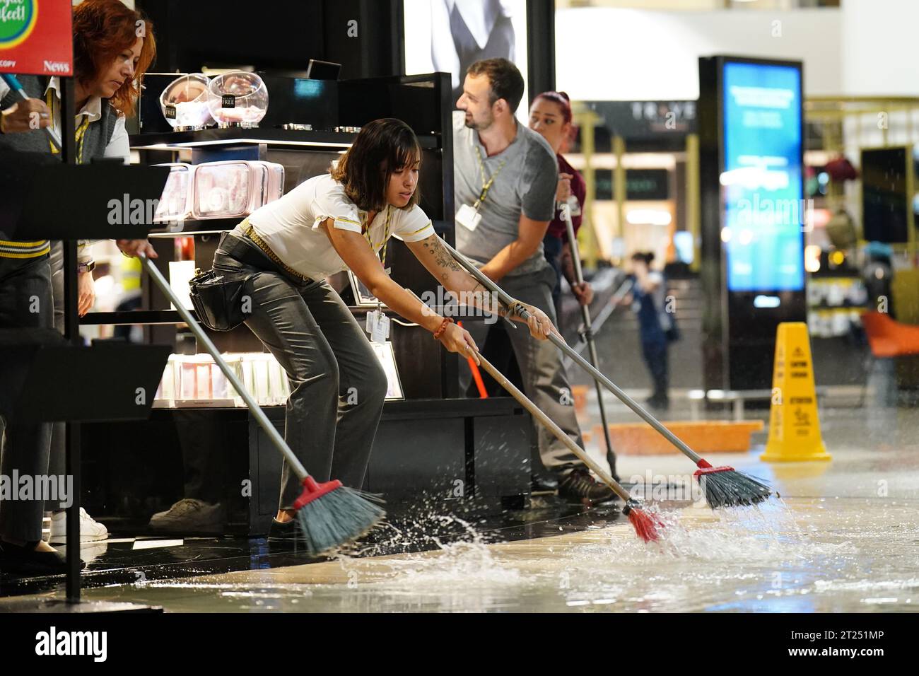 Staff sweep away water from inside Faro airport in Portugal after heavy ...