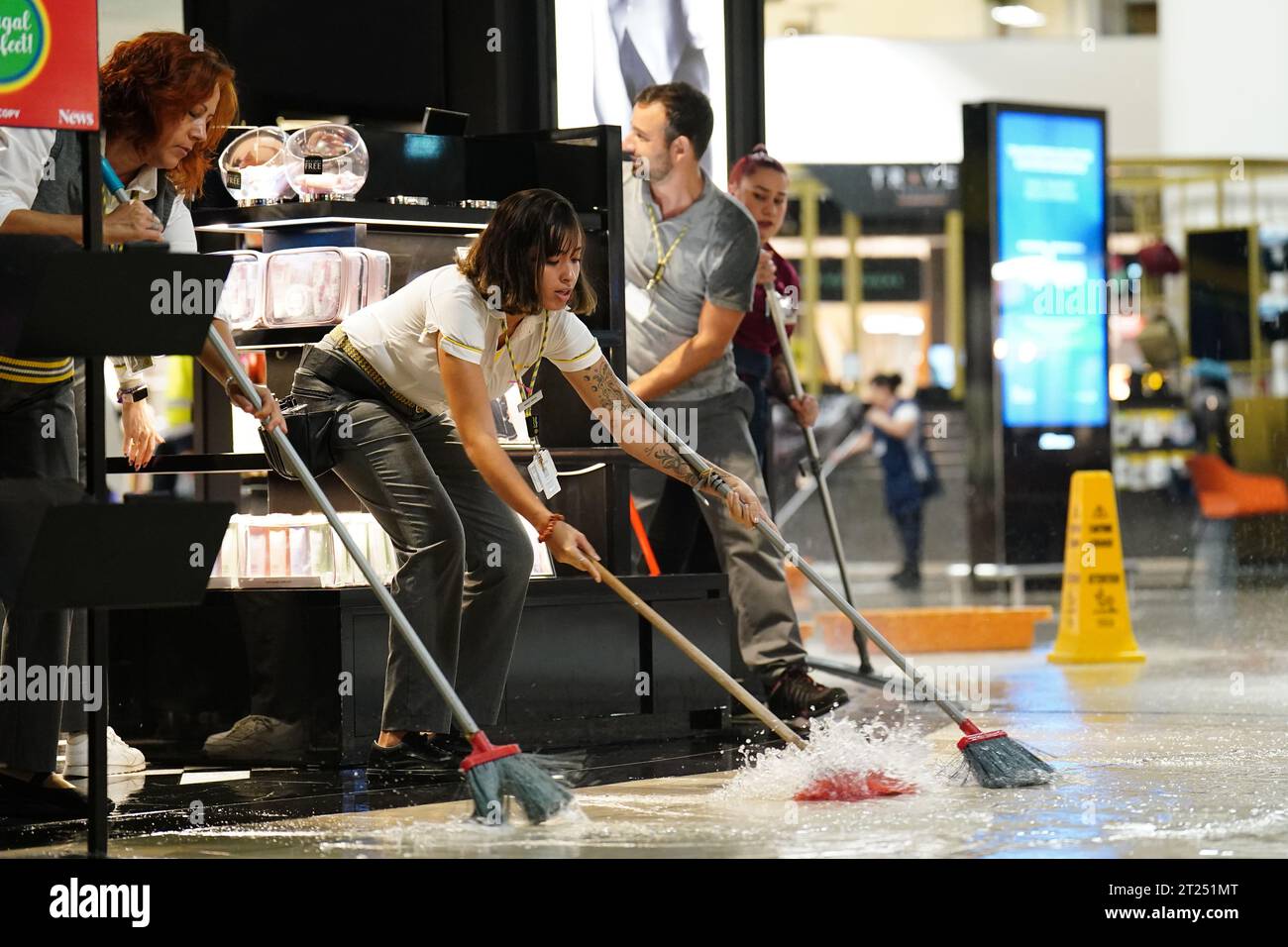 Staff sweep away water from inside Faro airport in Portugal after heavy ...