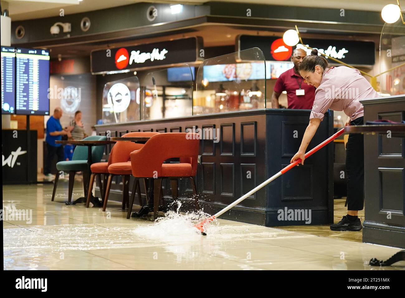 Staff sweep away water from inside Faro airport in Portugal after heavy ...