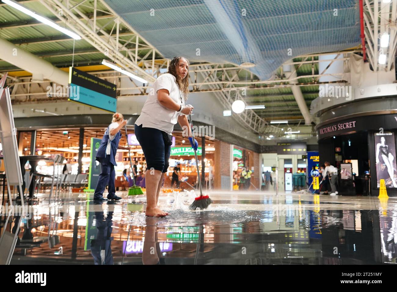 Staff sweep away water from inside Faro airport in Portugal after heavy ...
