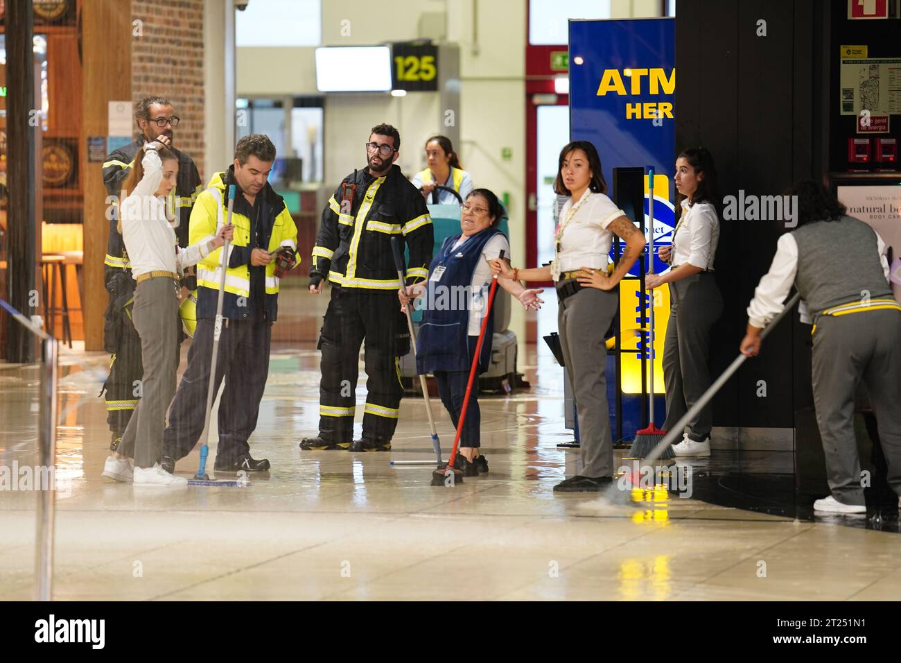 Staff sweep away water from inside Faro airport in Portugal after heavy ...