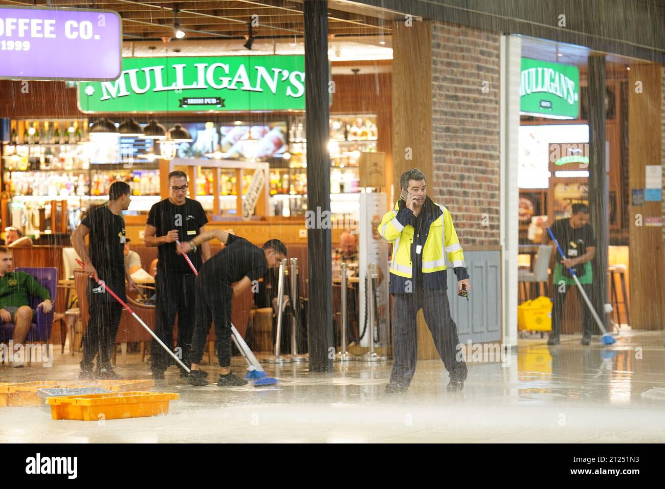 Staff sweep away water from inside Faro airport in Portugal after heavy ...