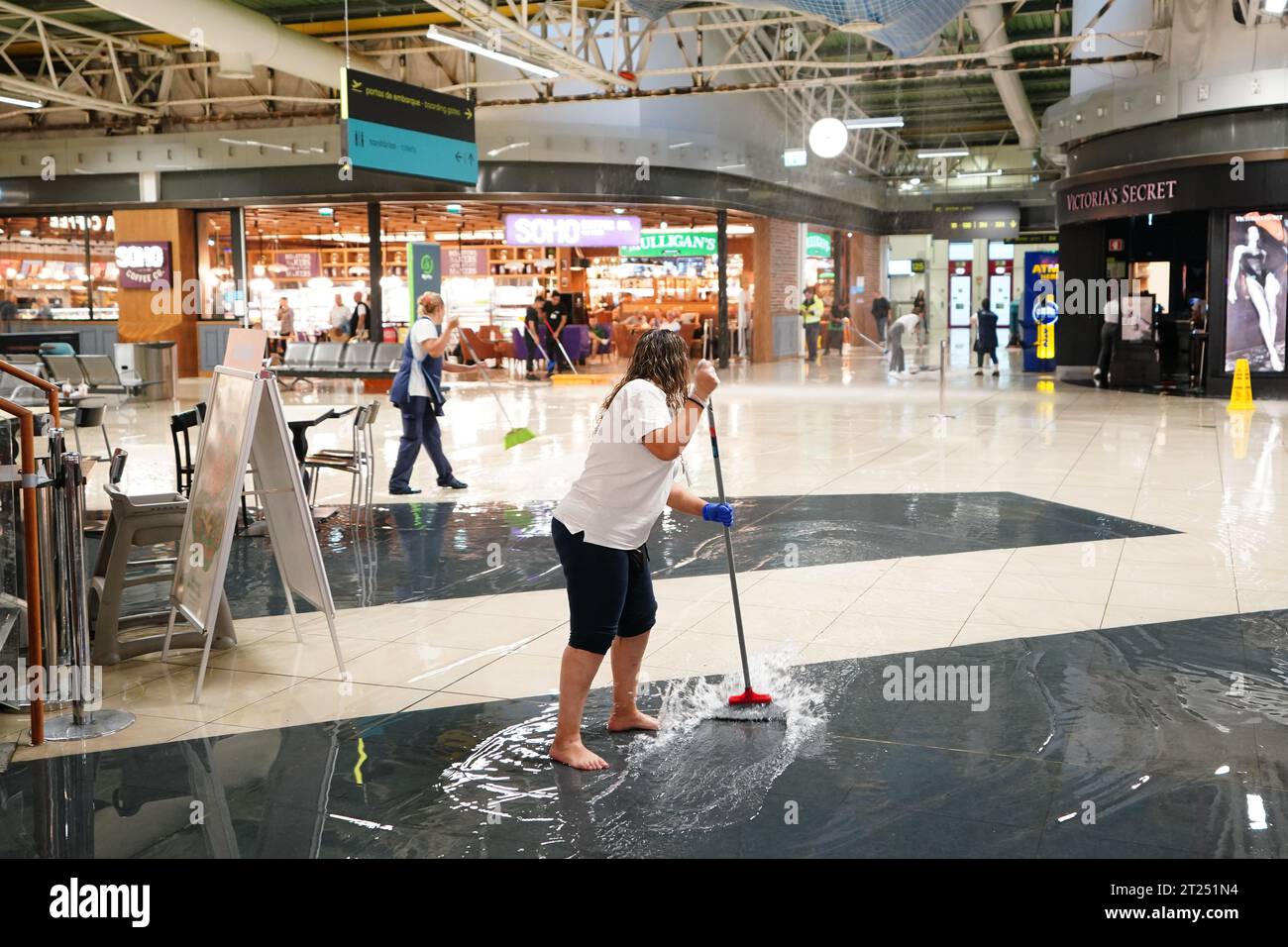 Staff sweep away water from inside Faro airport in Portugal after heavy ...