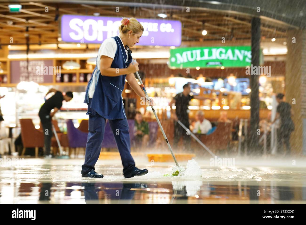 Staff sweep away water from inside Faro airport in Portugal after heavy ...