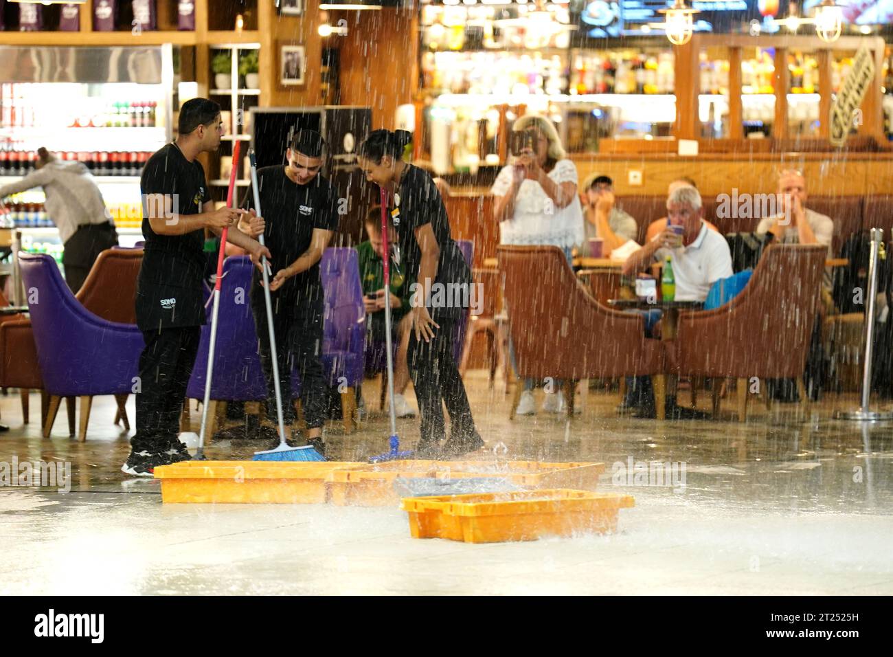 Staff sweep away water from inside Faro airport in Portugal after heavy ...