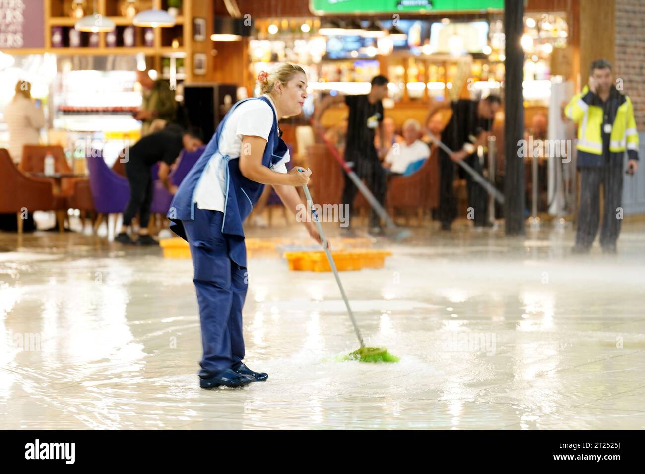 Staff sweep away water from inside Faro airport in Portugal after heavy ...