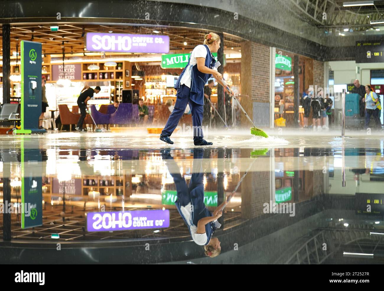 Staff sweep away water from inside Faro airport in Portugal after heavy ...