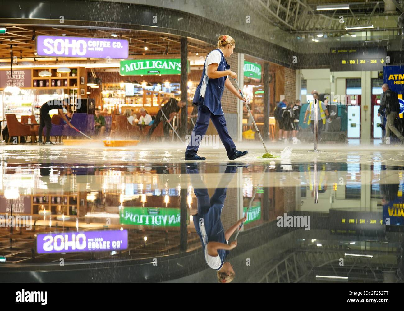 Staff sweep away water from inside Faro airport in Portugal after heavy ...