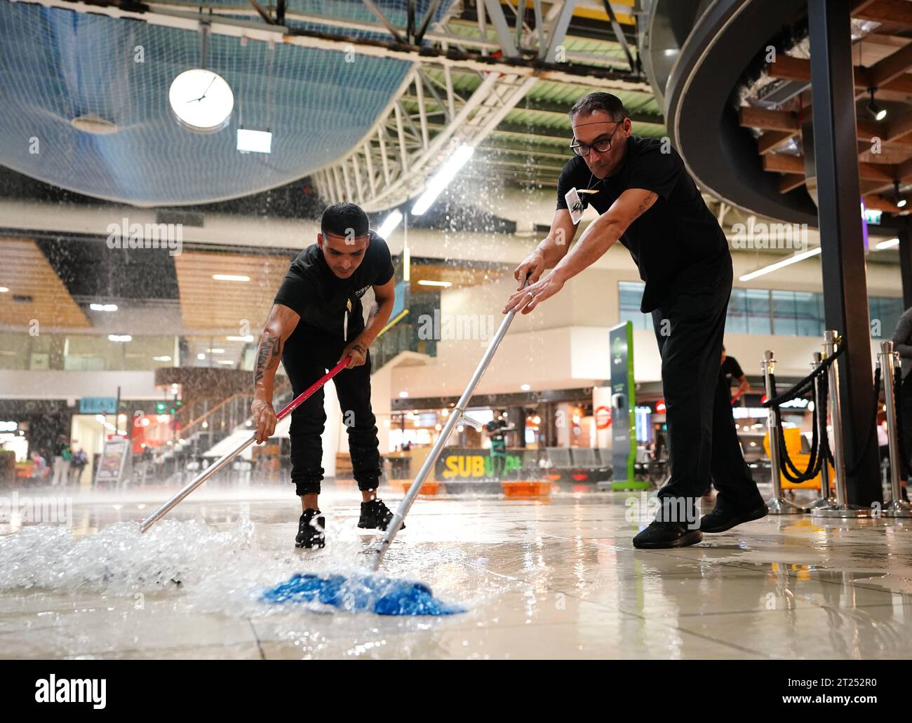 Staff sweep away water from inside Faro airport in Portugal after heavy ...