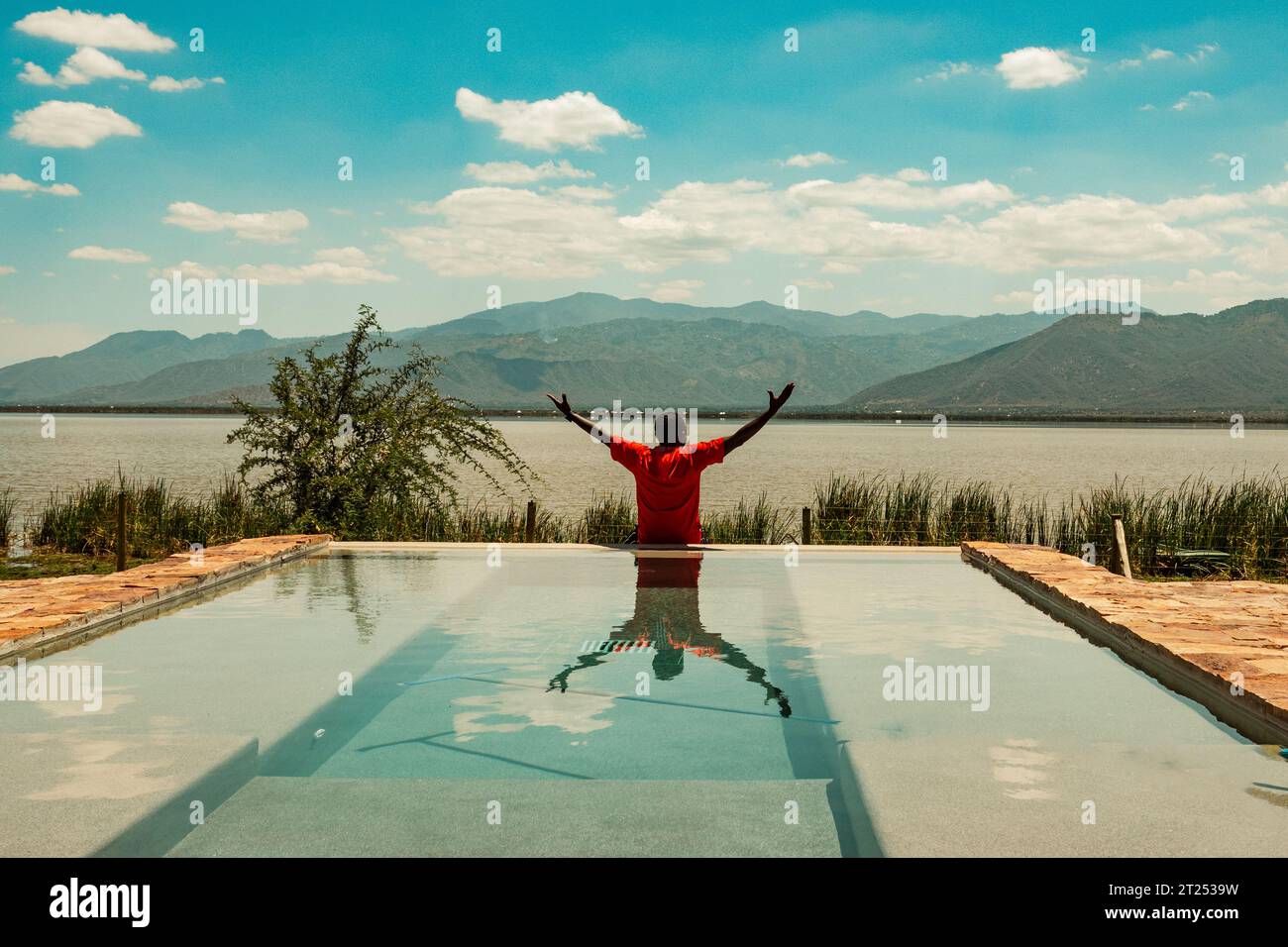 A man in an infinity swimming pool at Lake Jipe at Tsavo West National ...