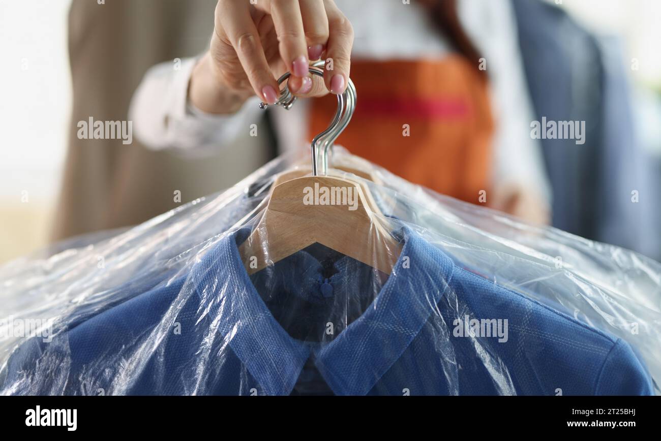 Worker giving to client clean clothes hanging on hangers at dry ...