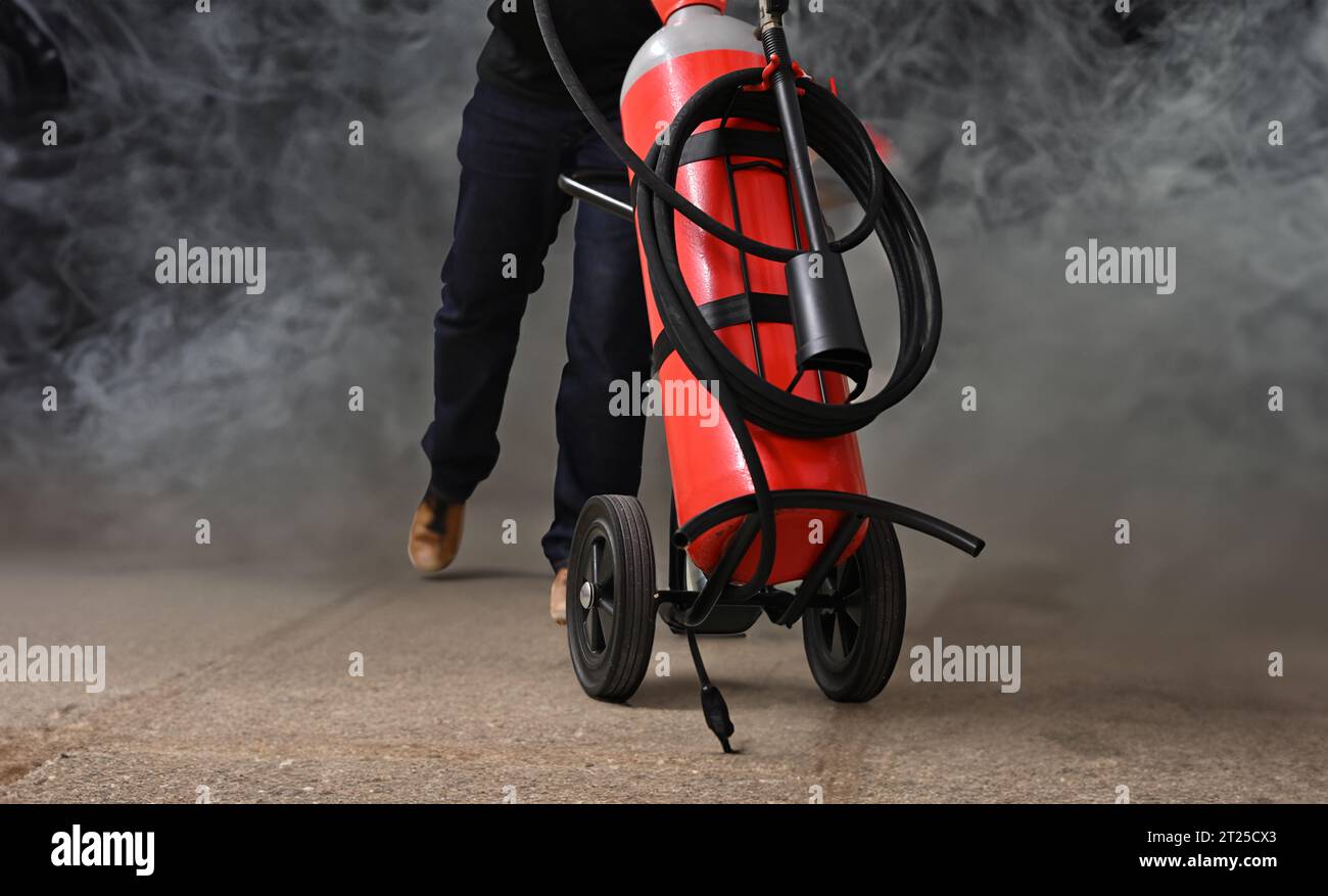 Man runs with a movable fire extinguisher through smoke during a ...