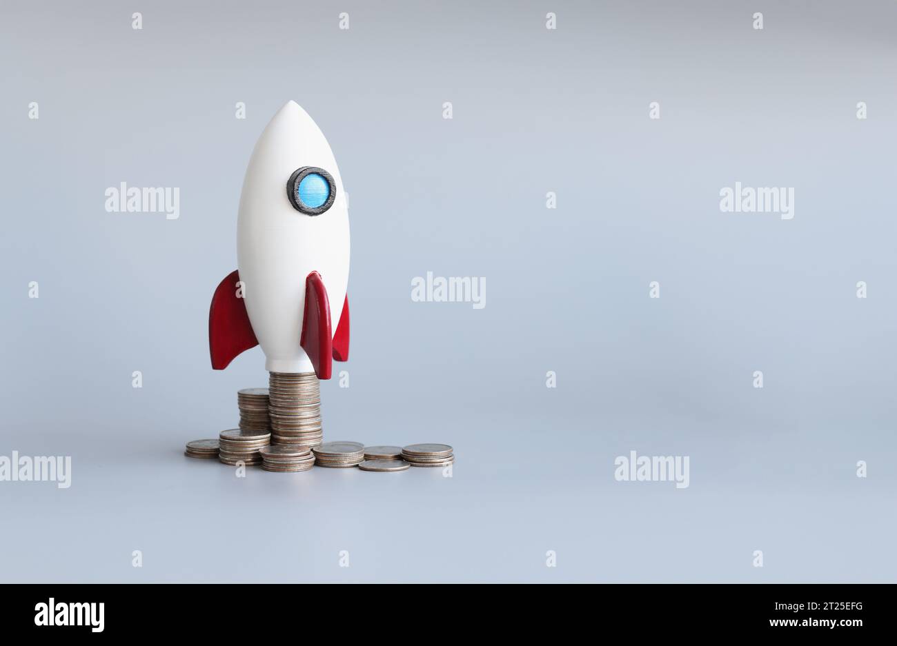 Miniature rocket stand on stack of coins, rocketship as symbol to open ...